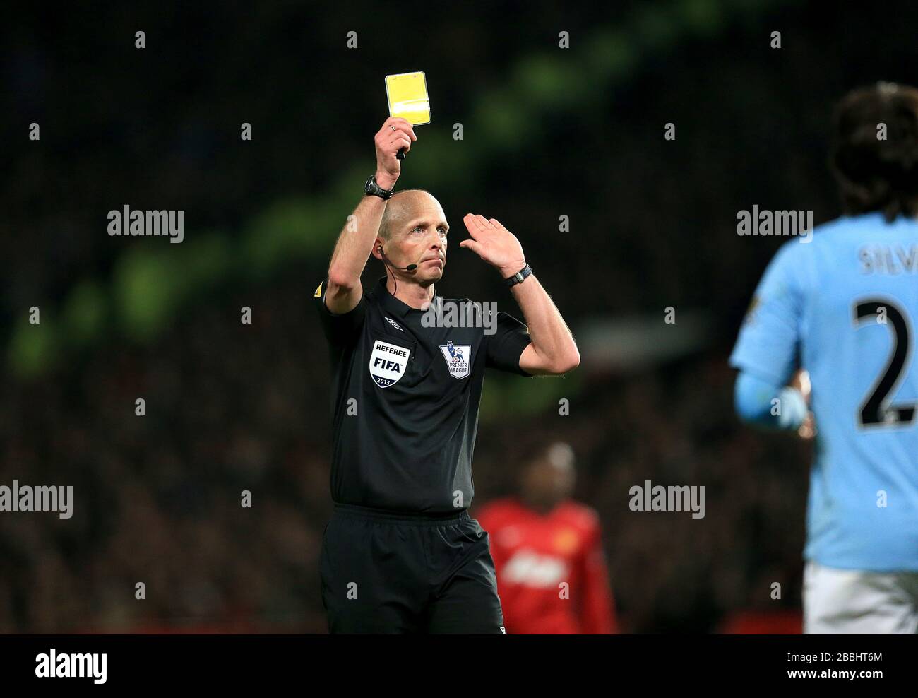 Referee Mike Dean issues a yellow card to Manchester City's David Silva ...