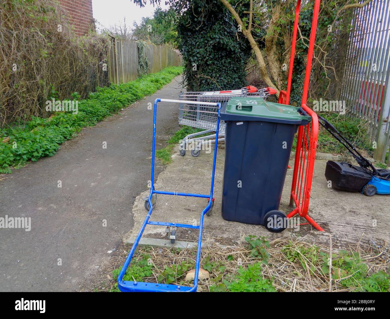 Fly-tipping on the side of a country lane with wire frame and old lawn ...