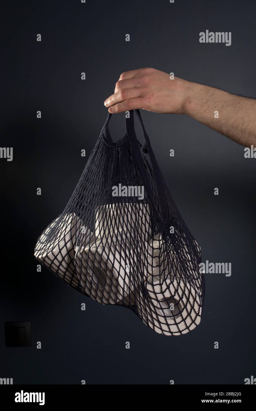 Man's hand holds a string bag with rolls of toilet paper Hygiene ...