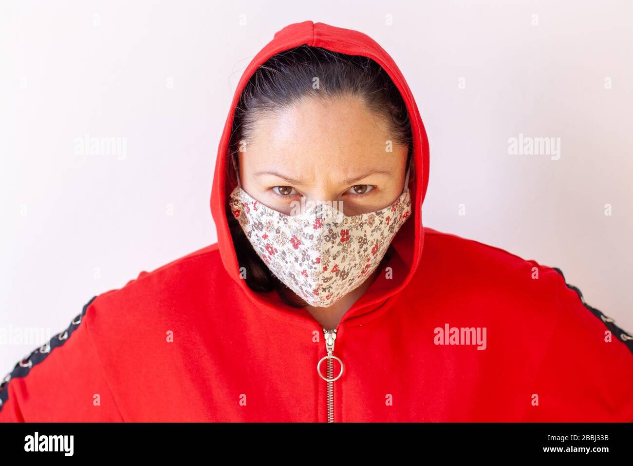 A girl in a colored mask and a red hood is angrily looking at the ...