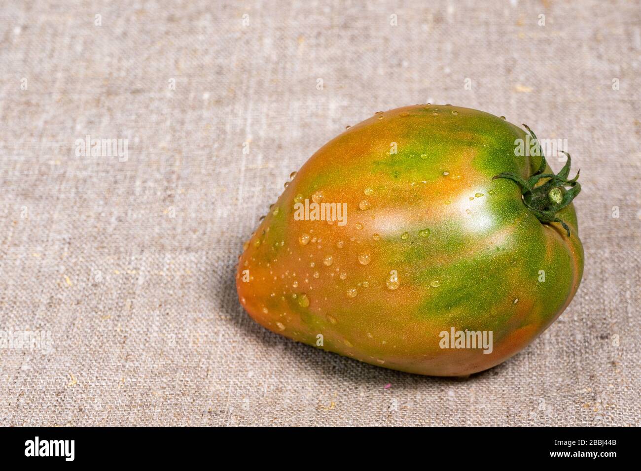 Unripe yellow-green large tomato on a mat Stock Photo - Alamy