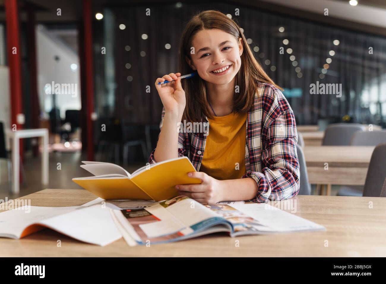 Image of smiling caucasian girl doing homework with exercise books ...