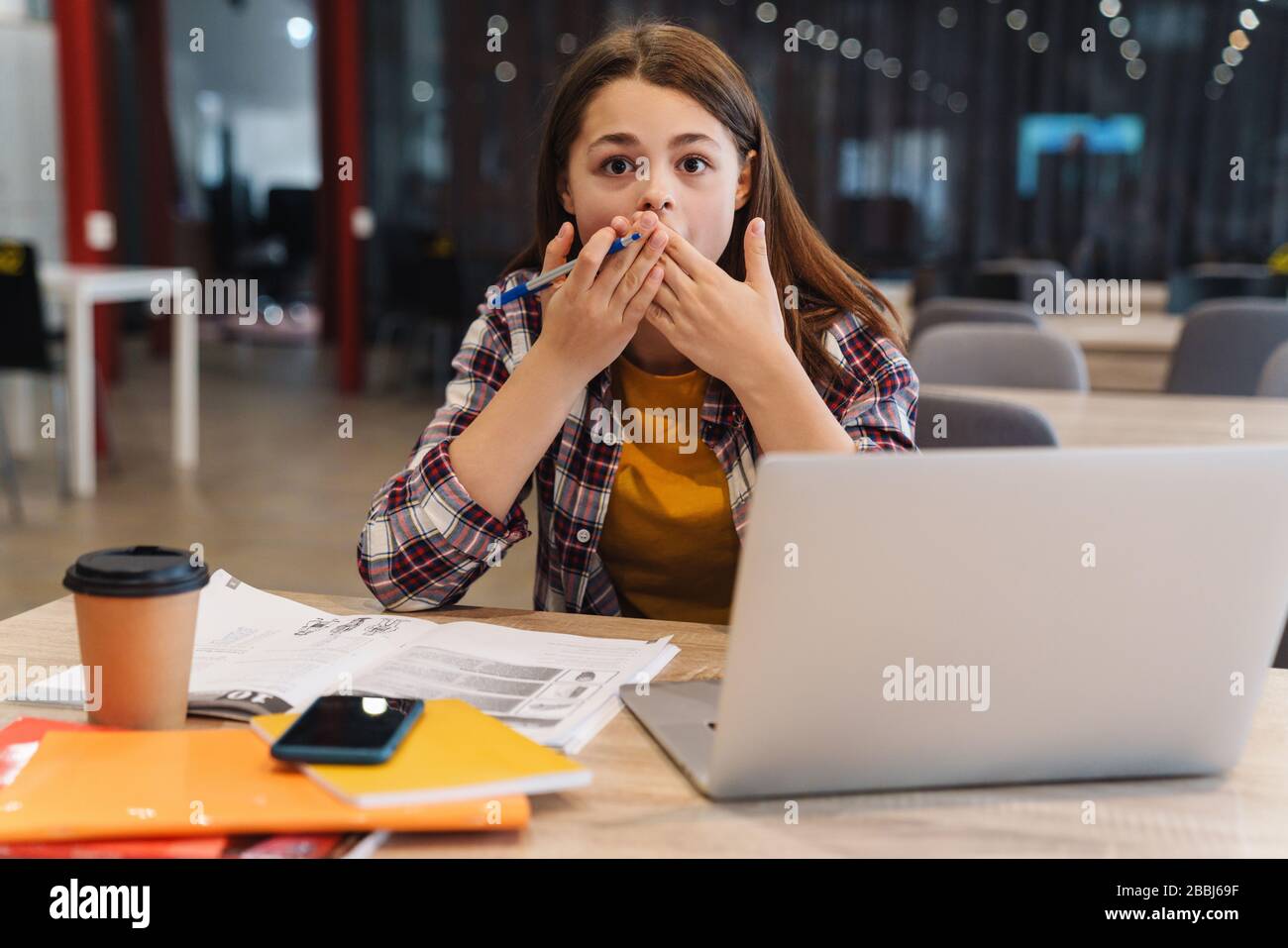 Image of shocked girl doing homework with laptop and exercise books ...