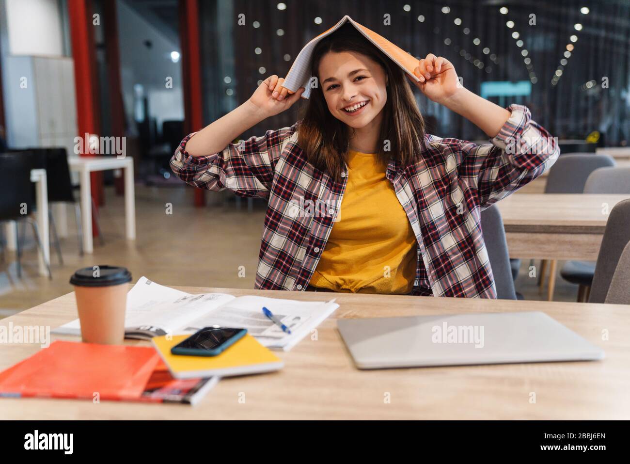 Image of smiling caucasian girl making fun with exercise books while ...