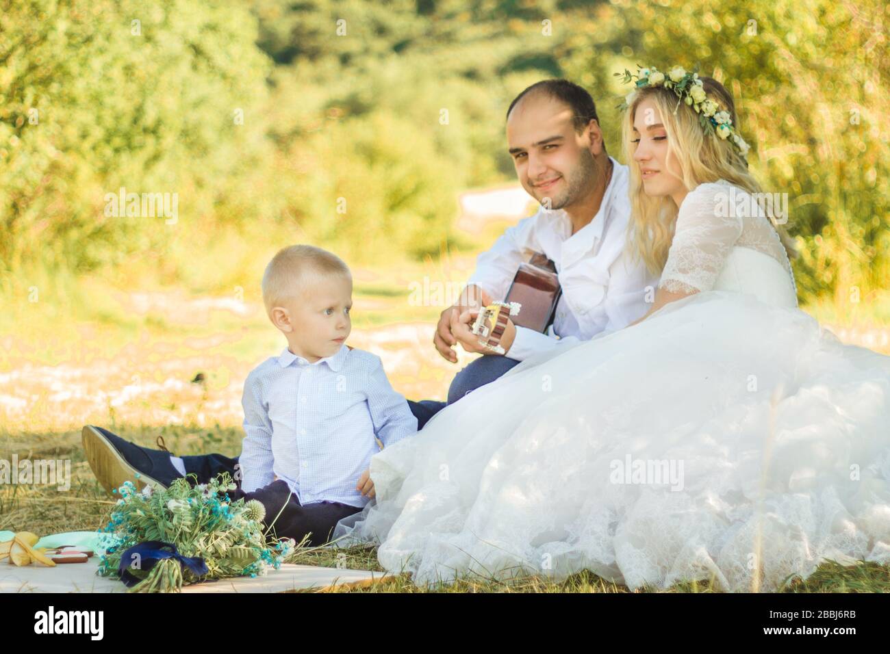 Picnic style outdoor wedding. Groom playing on guitar, young attractive ...