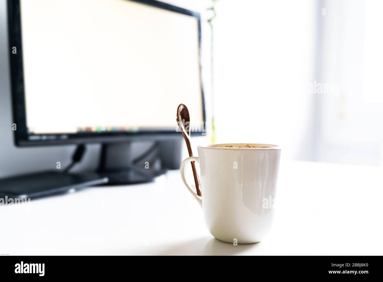 Coffee cup with a spoon in front of the computer on a desk Stock Photo ...