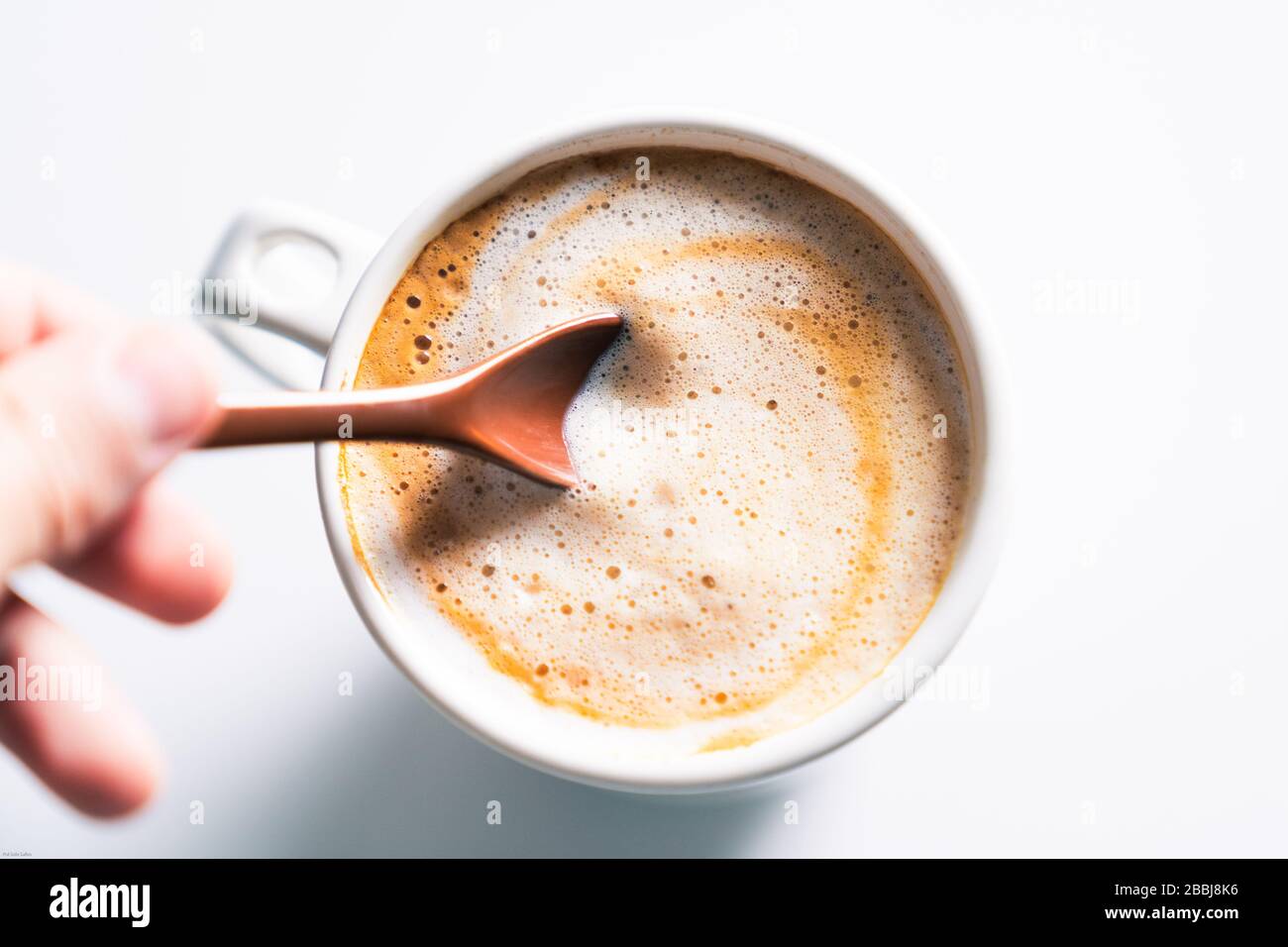 Hand stirring a cup of creamy coffee with a ceramic spoon Stock Photo ...