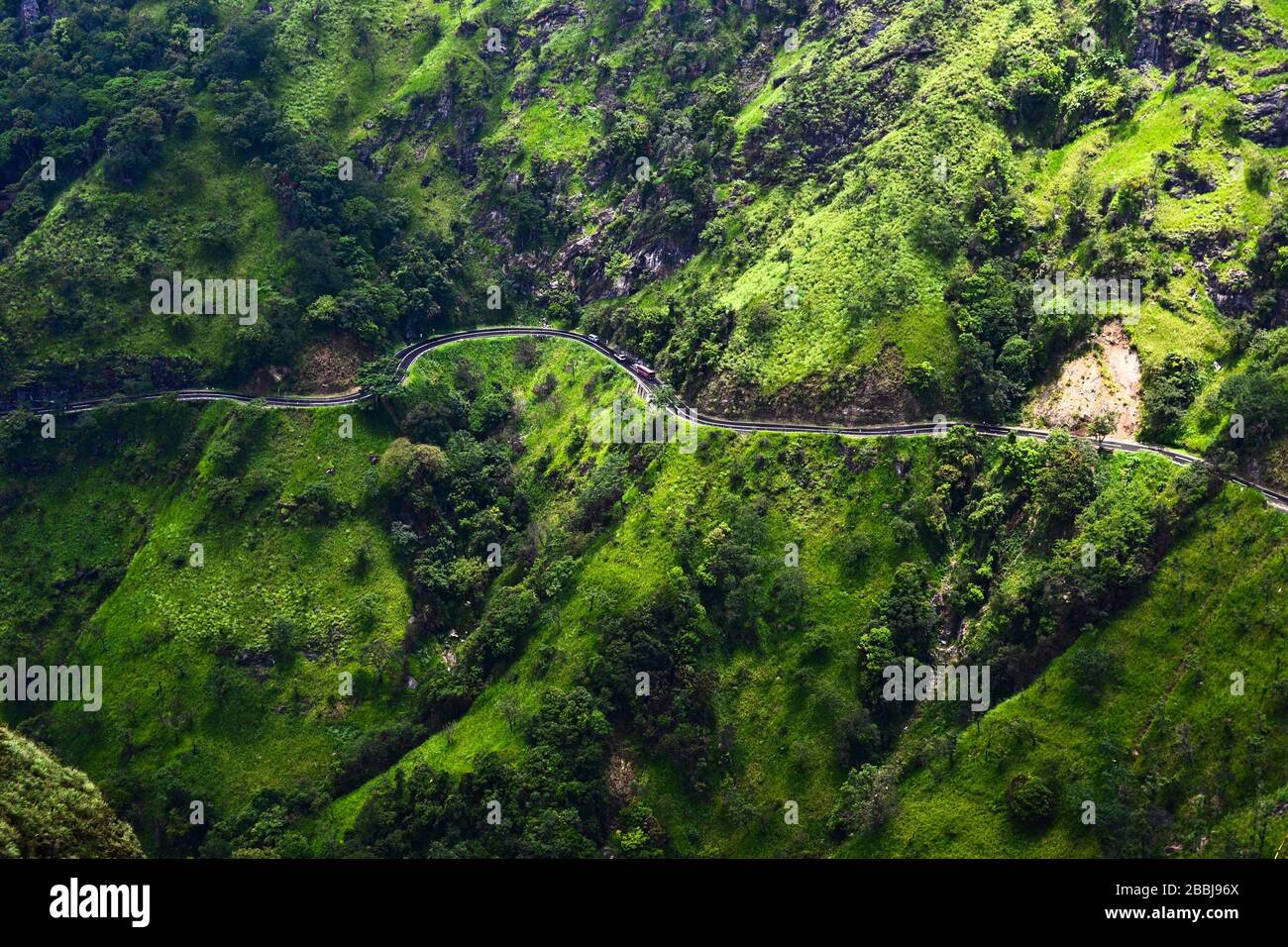 Curved mountain road with cars and bus from aerial view. Bright green ...
