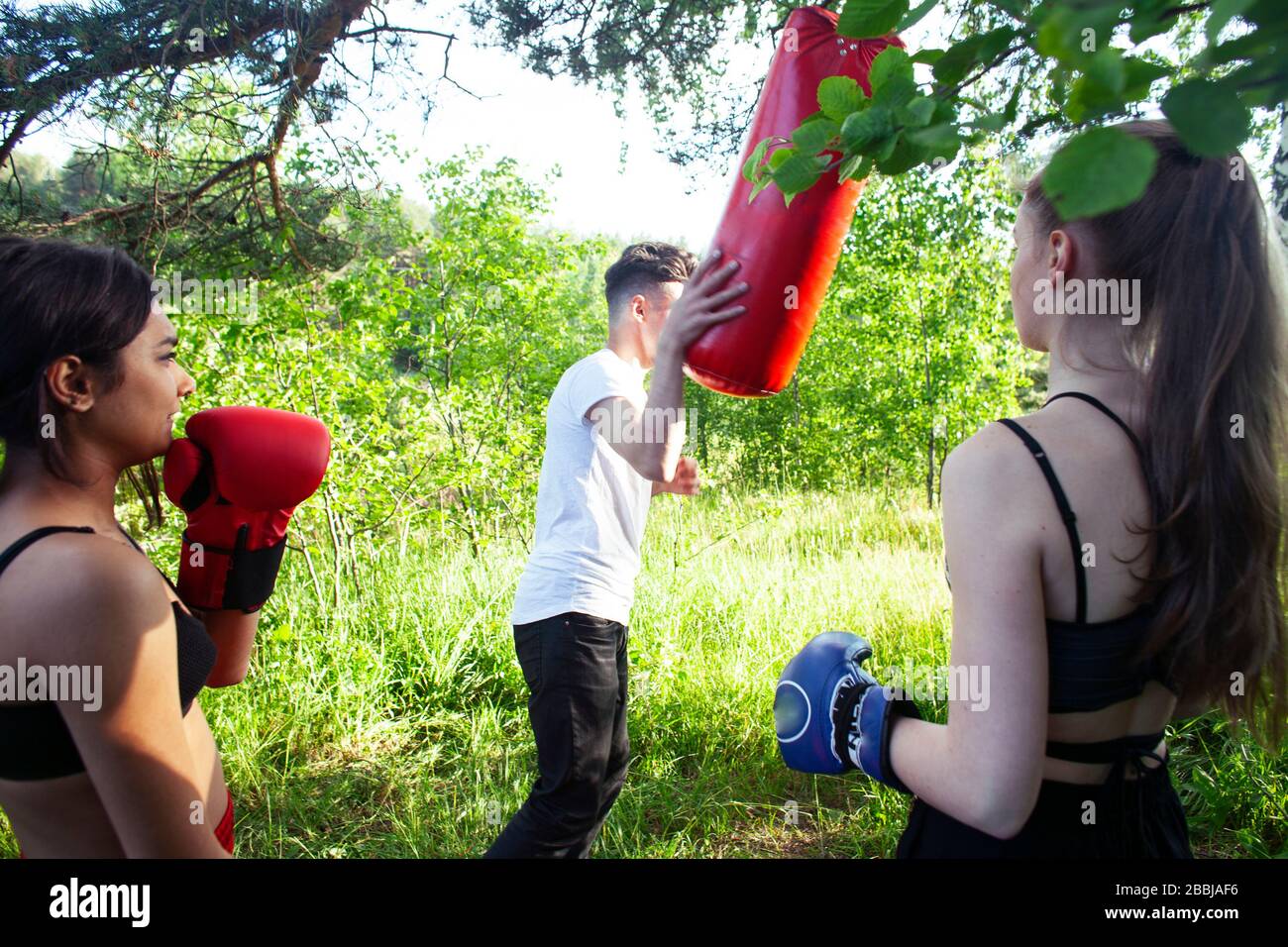 girls fighting boxing outside with coach in green park, sport summer ...