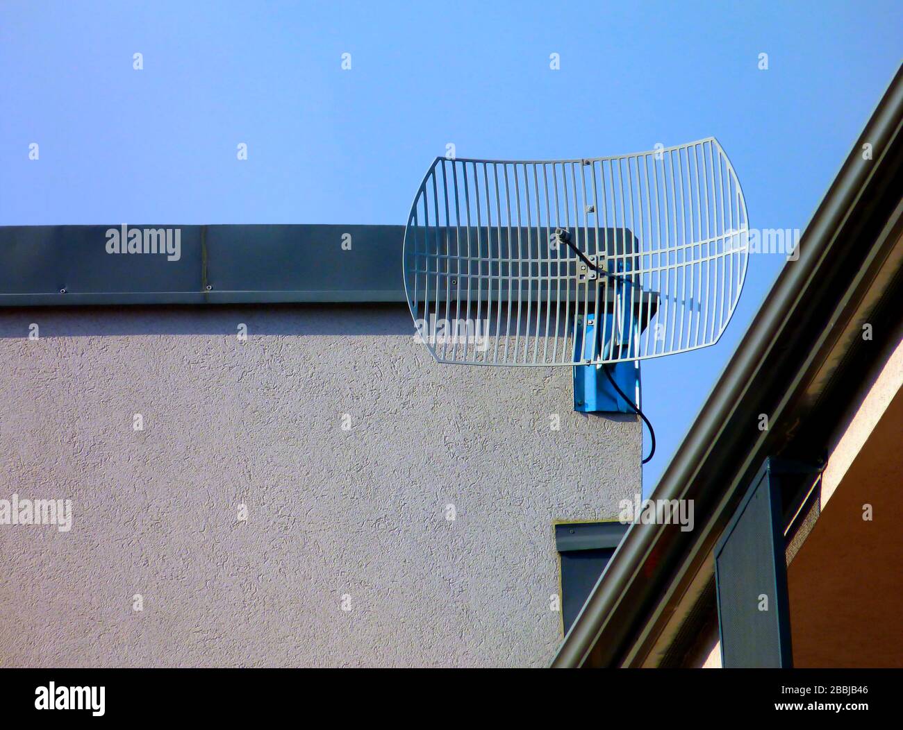 Wire framed satellite dish signal receiver near roof top of multi unit ...