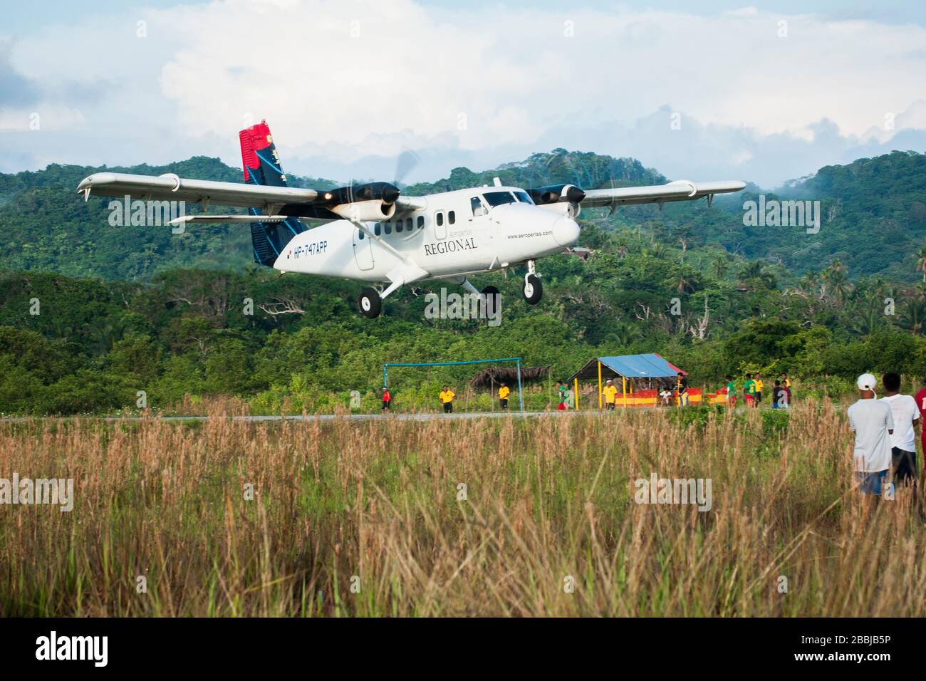 Small commercial airplane flying low over soccer field to land on an ...