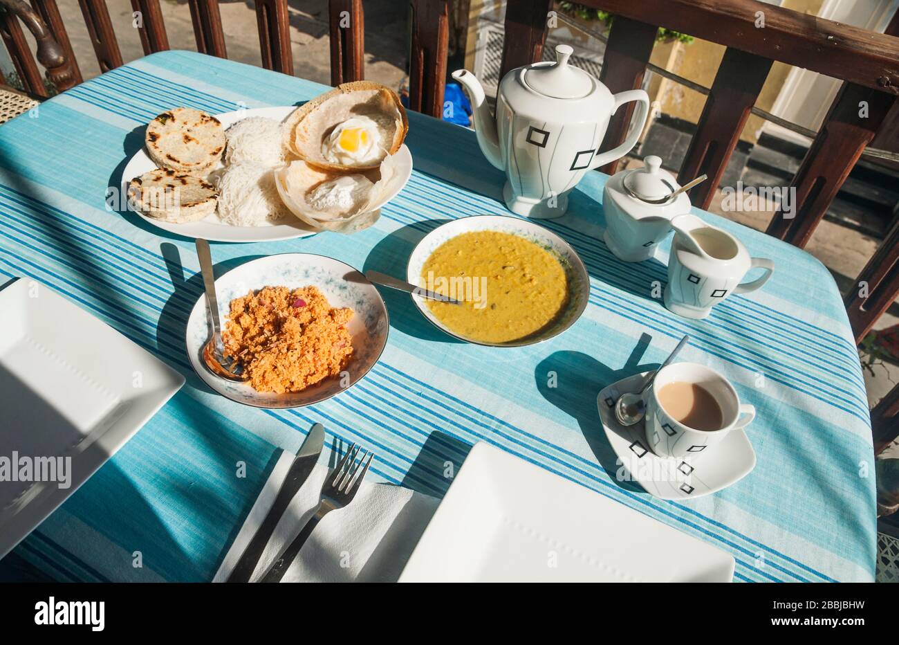Traditional breakfast of roti, egg hoppers, dal, and rice on a balcony ...