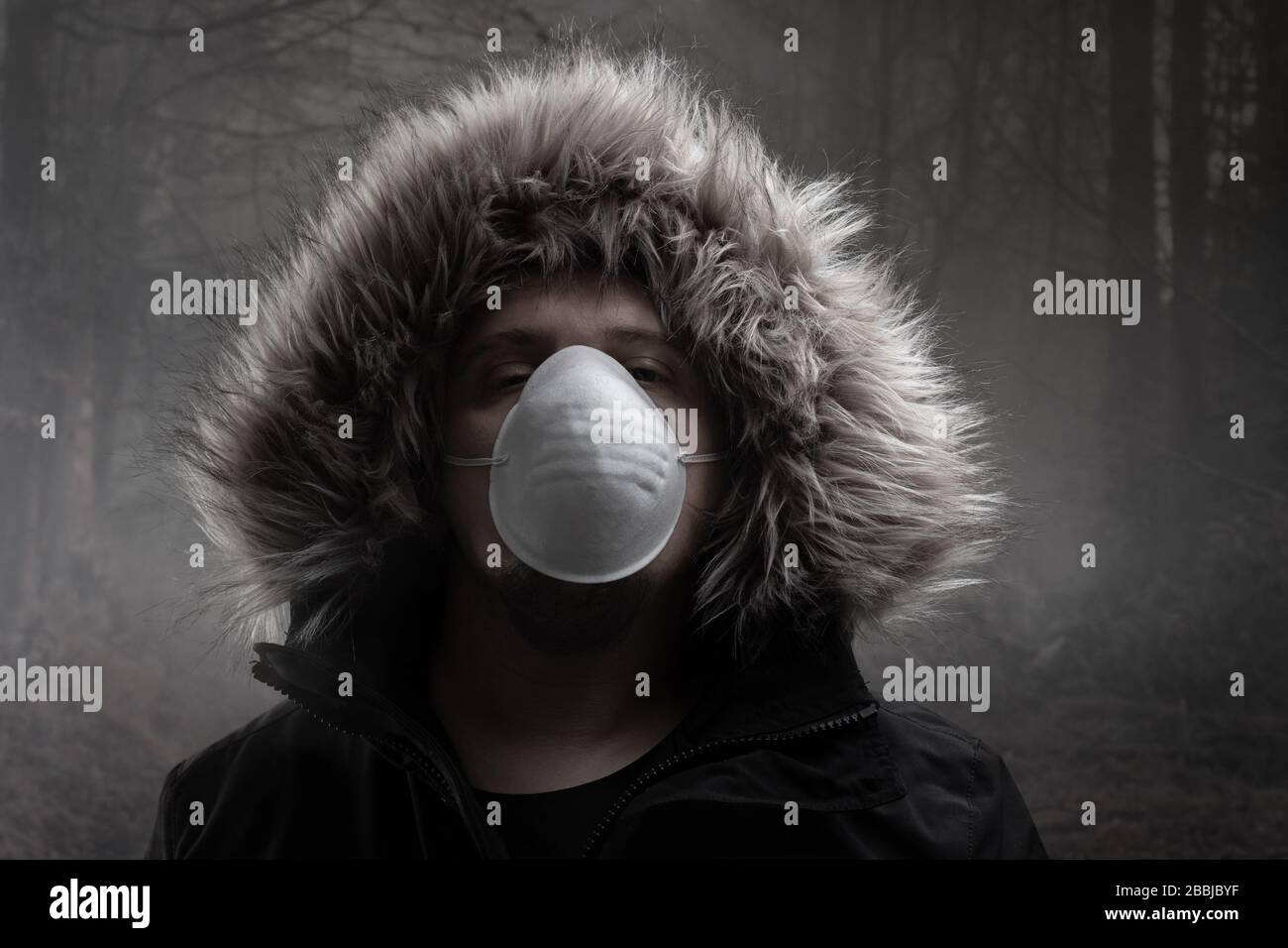 portrait of man with protective mask and coat in front of misty forest ...