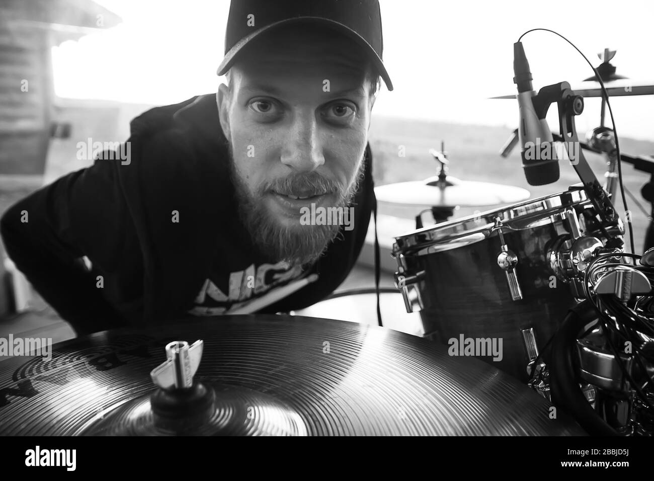 BW portrait of a beard drummer with drum sticks in his hands sitting ...