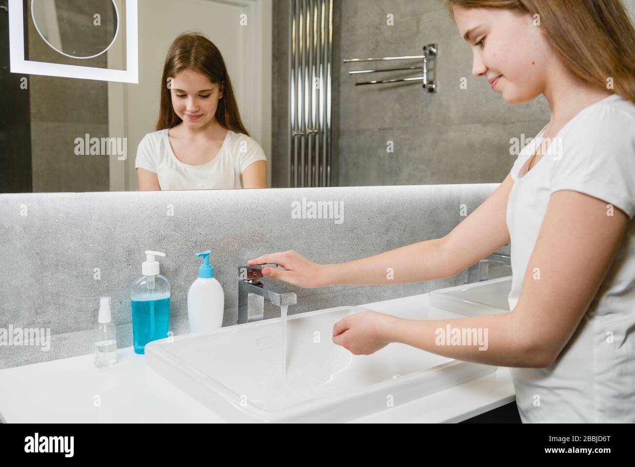 Girl open water tap to wash hands Stock Photo - Alamy