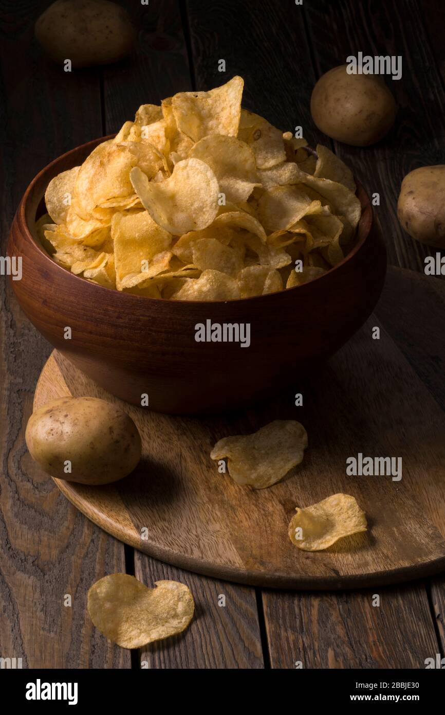 Potato chips in a bowl on a rustic wooden background with whole ...