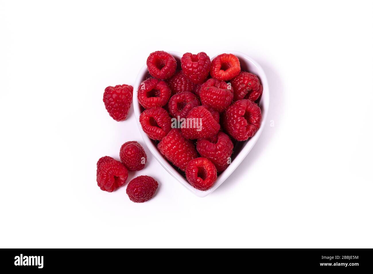 Fresh raspberries in a heart-shaped bowl isolated on a white background ...
