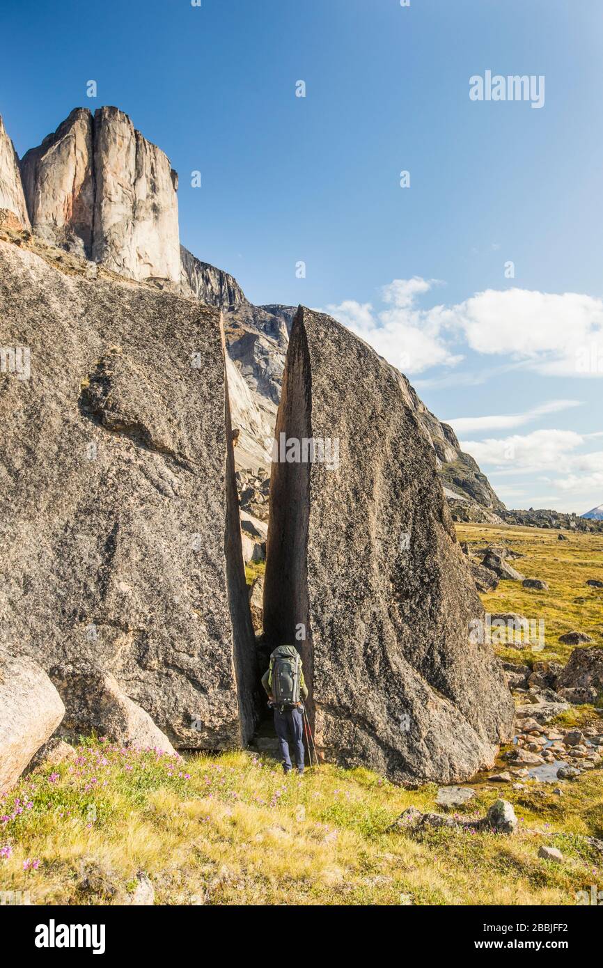 Backpacker squeezes through gap in cracked erratic boulder Stock Photo ...
