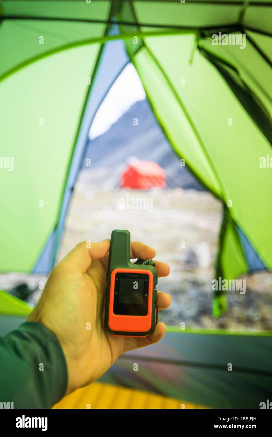 Man holds GPS and satellite safety communication device in tent Stock ...
