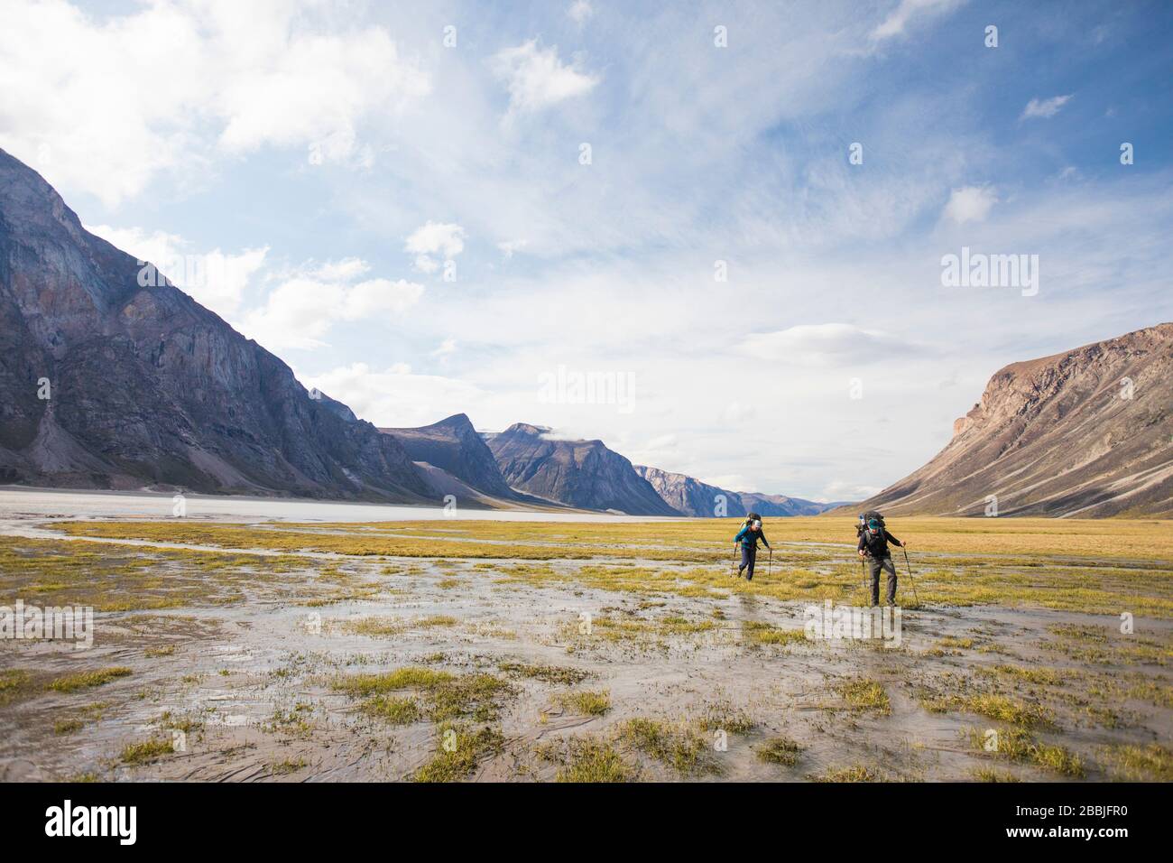 Two backpackers cross wet swamp land in Akshayak Pass Stock Photo - Alamy