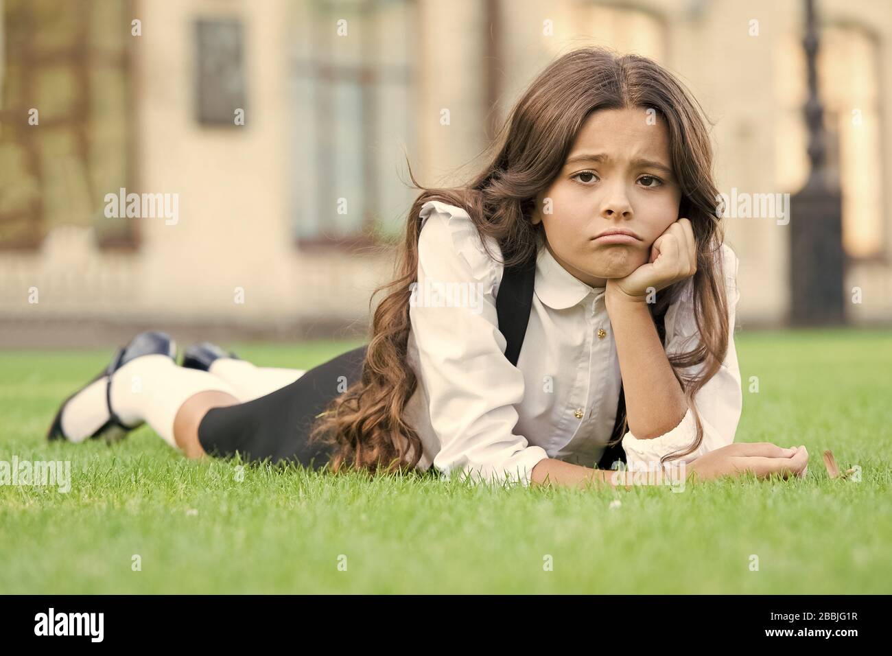 Sad without a smile. Sad schoolgirl relax on green grass. Adorable ...