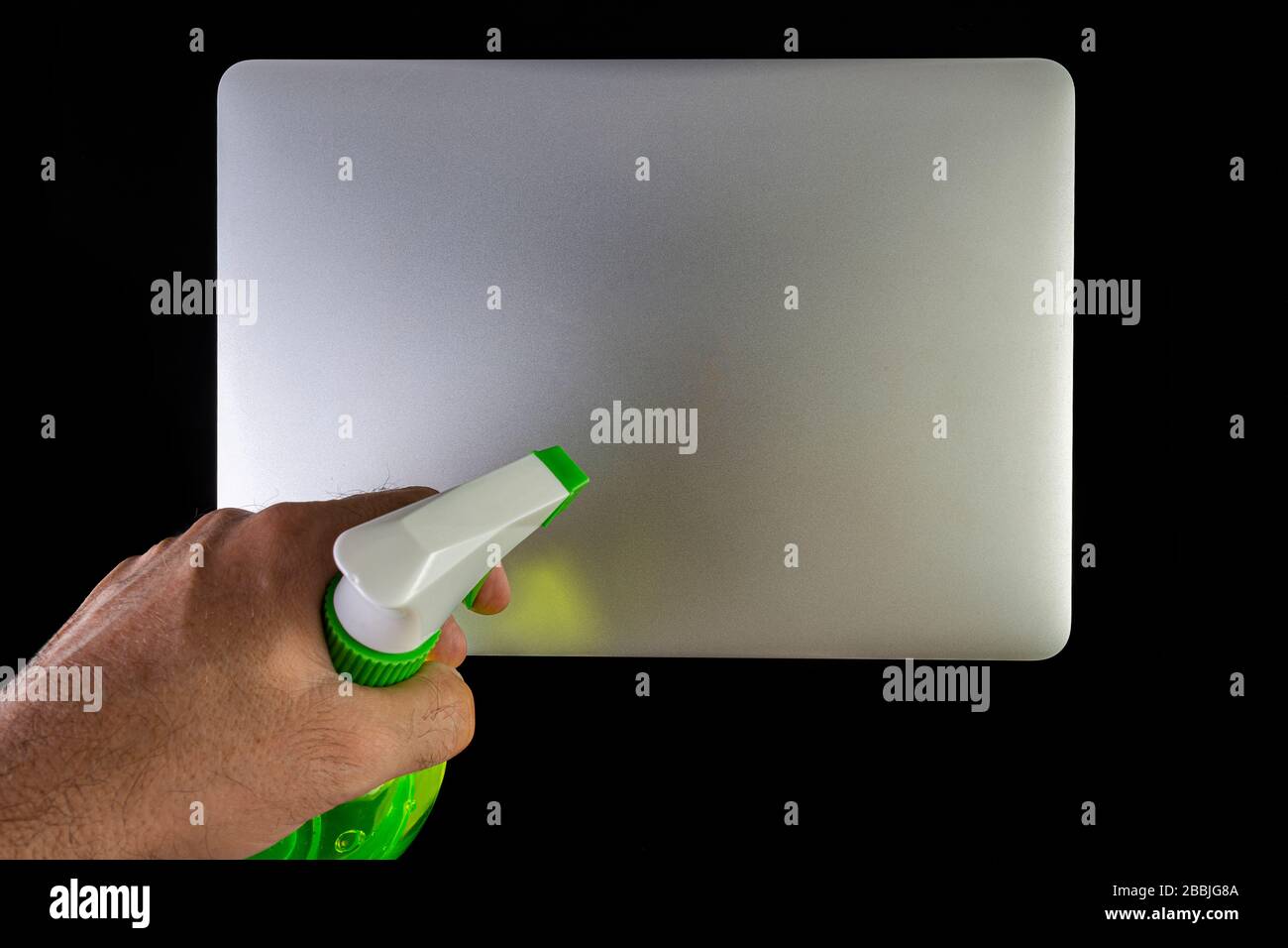 Hand cleaning a laptop with a spray bottle sanitizer Stock Photo - Alamy