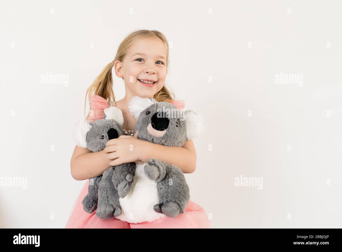 Cute blond little girl hugging koala stuffed animals indoors Stock ...