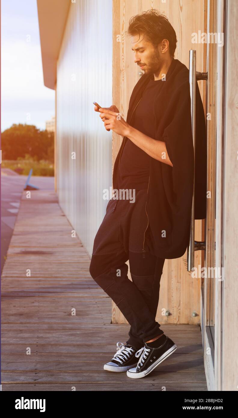 A man in a fashionable black outfit posing at the sunset of a warm ...