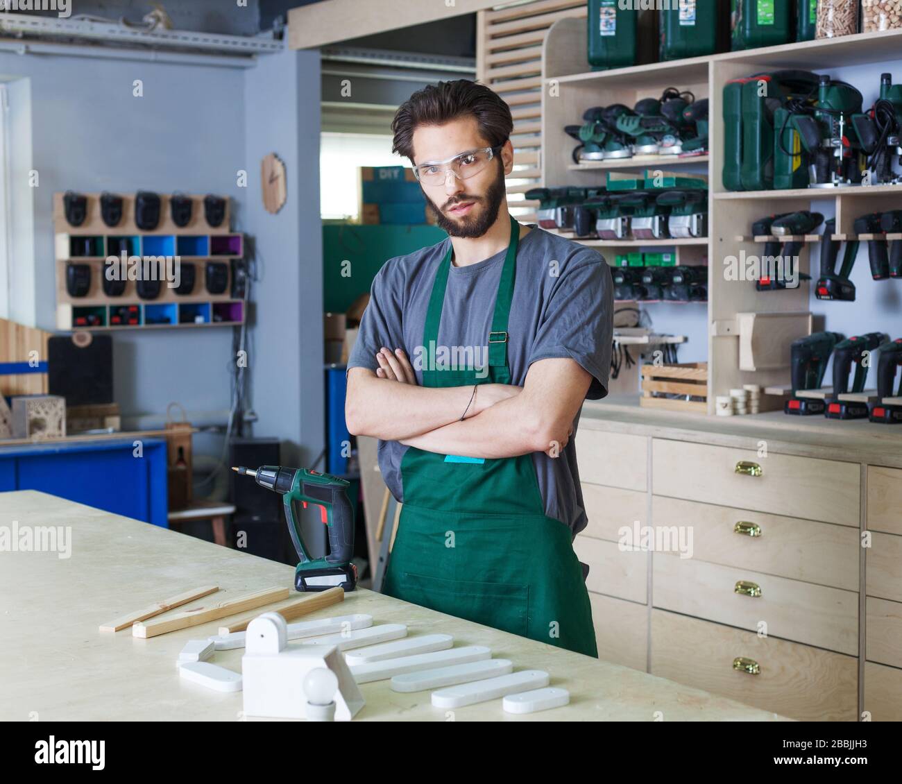 Smiling woodworker. Cheerful young male carpenter leaning at the wooden ...