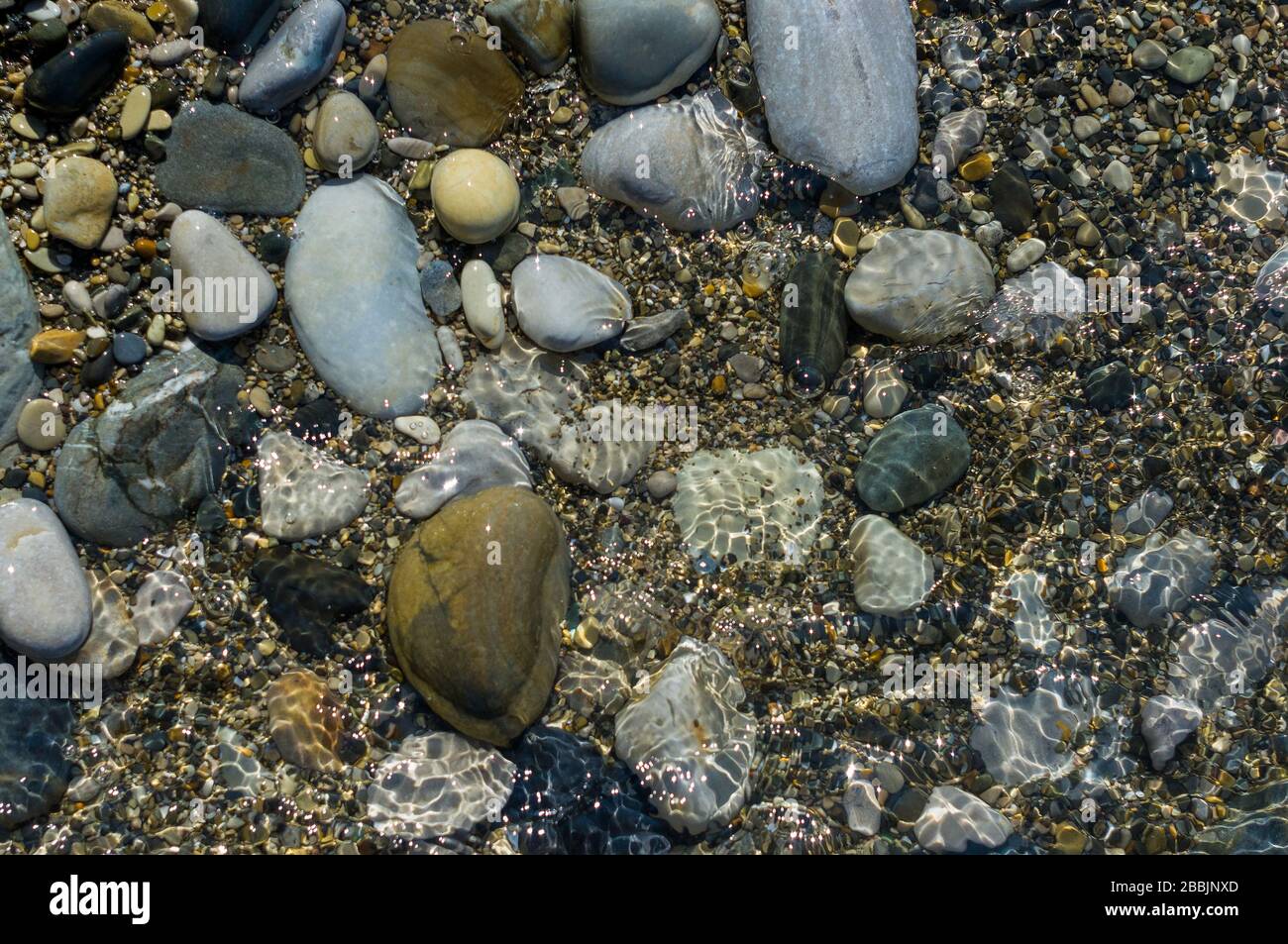 pebble stones on the sea beach, the rolling waves of the sea with foam ...