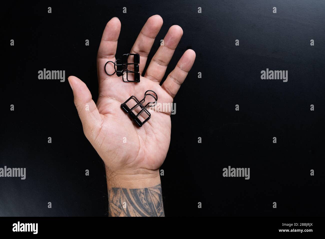 A man hand holdind black paper clips isolated on Black background Stock ...