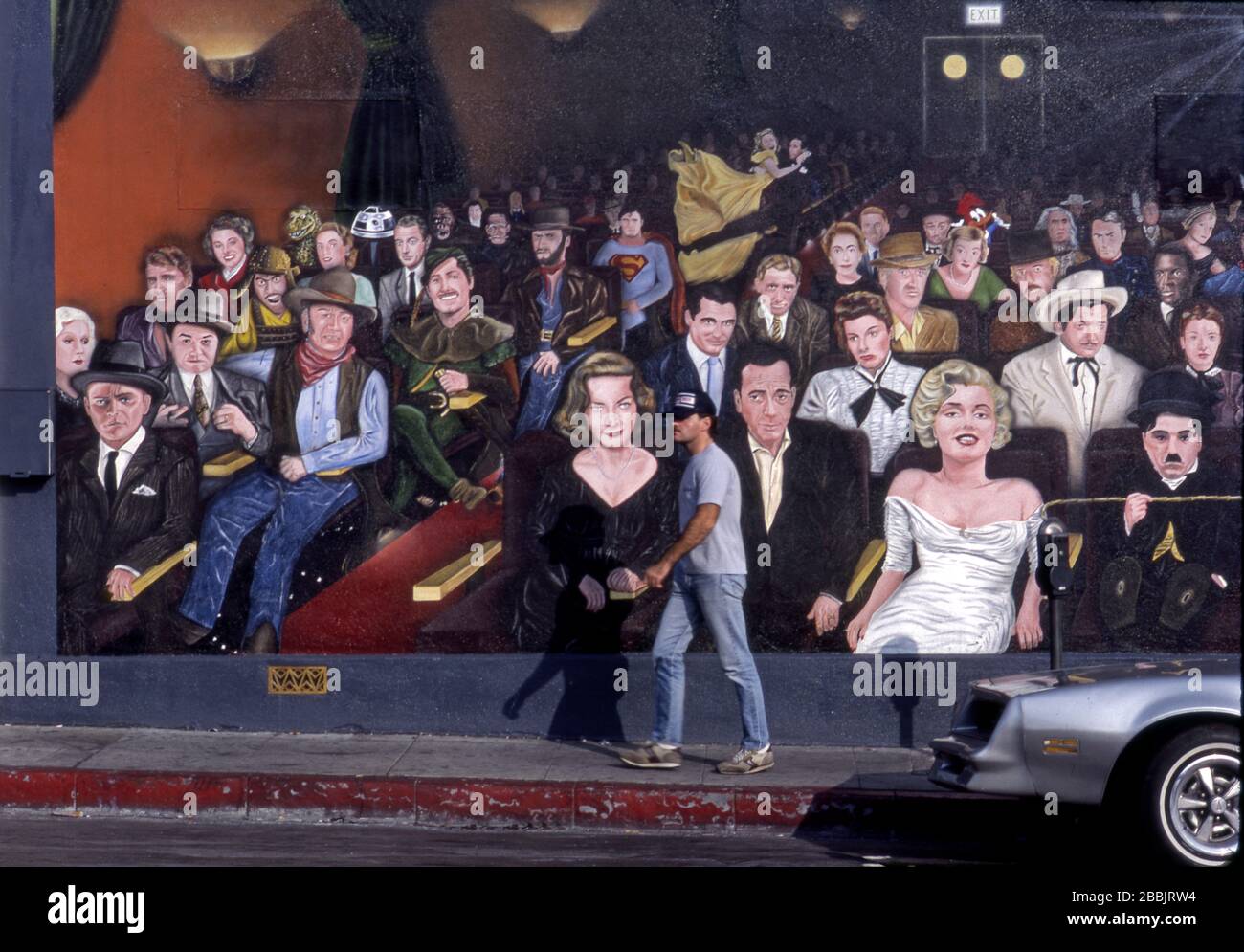 Man walking past mural depicting classic Hollywood movie stars titled ...