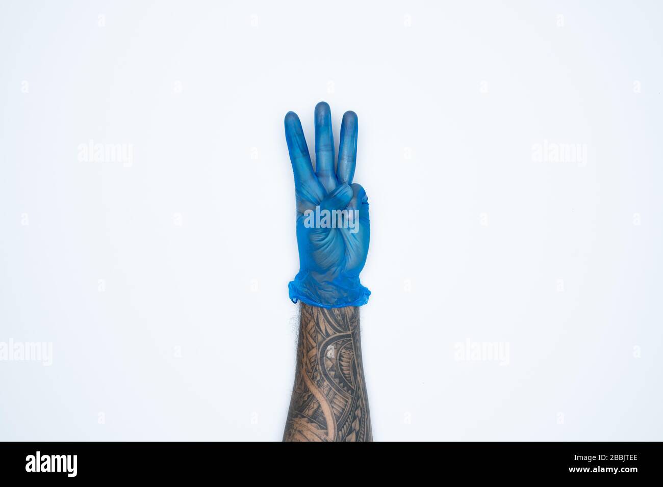 A man hand and gestures in Blue rubber glove shows three fingers sign ...