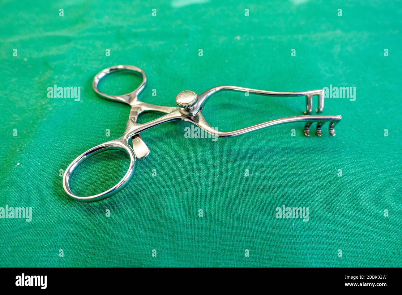 on a green surgical sheet lies a surgical retractor Stock Photo - Alamy