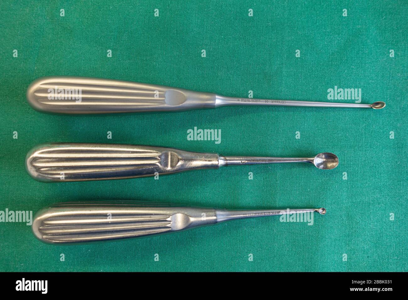 three differently sized sharp spoons for an operation lie on a green ...