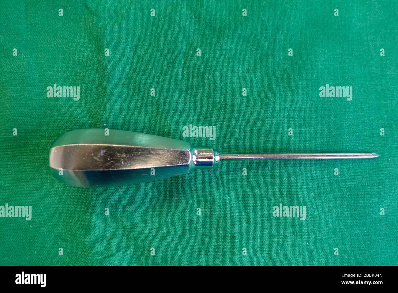 on a green surgical drape lies an awl for an operation Stock Photo - Alamy