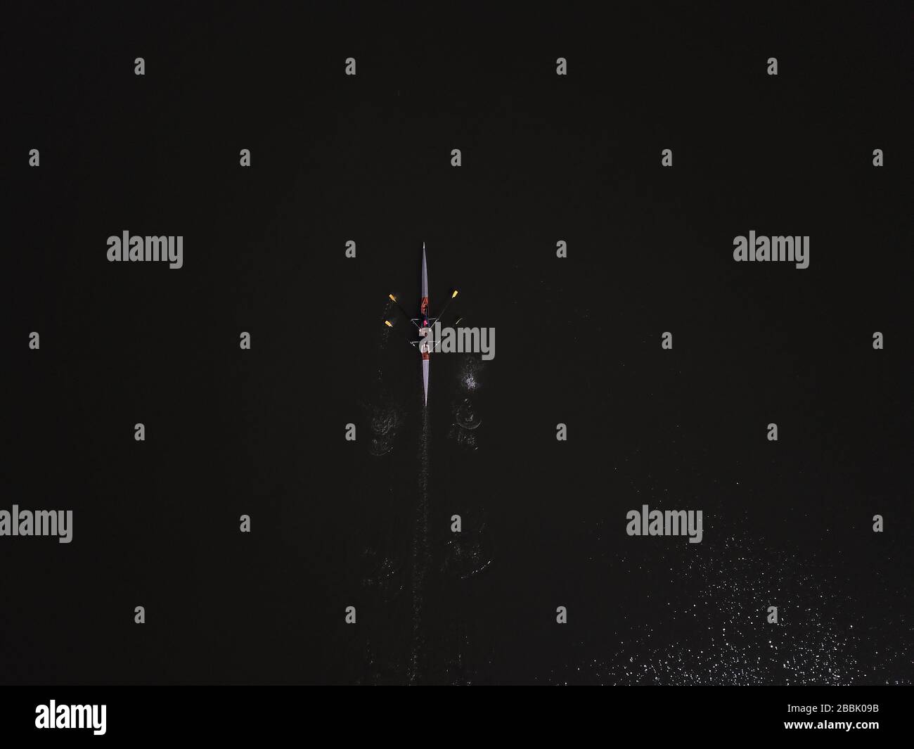 Four people rowing of black water Stock Photo - Alamy