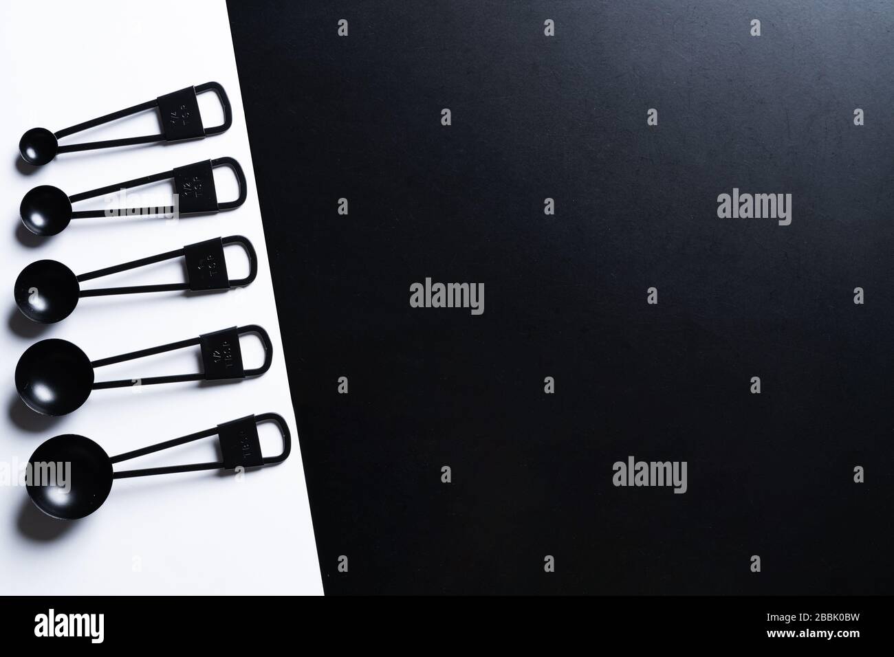 Black measuring spoons on black and white background Stock Photo - Alamy