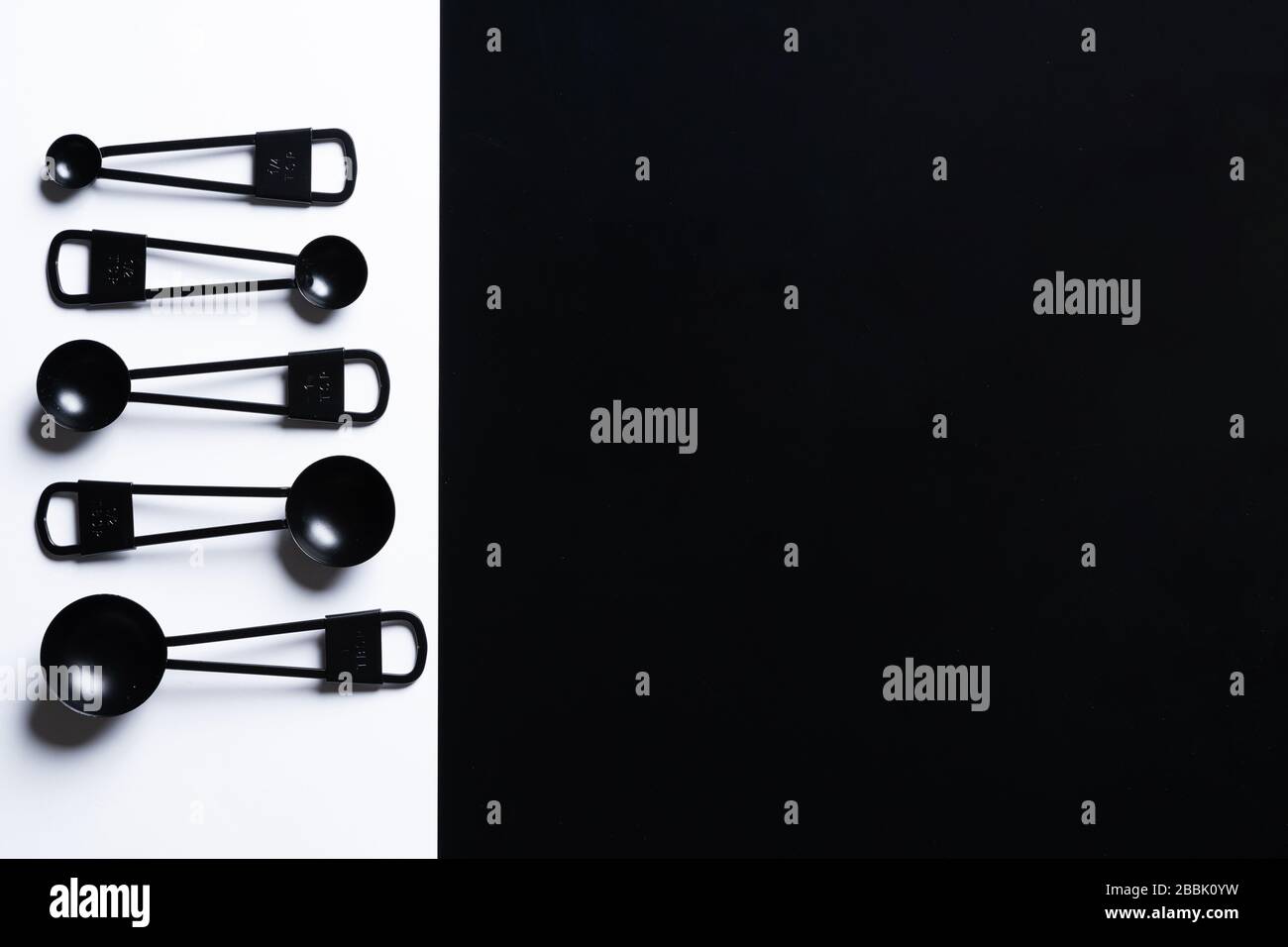Black measuring spoons on black and white background Stock Photo - Alamy