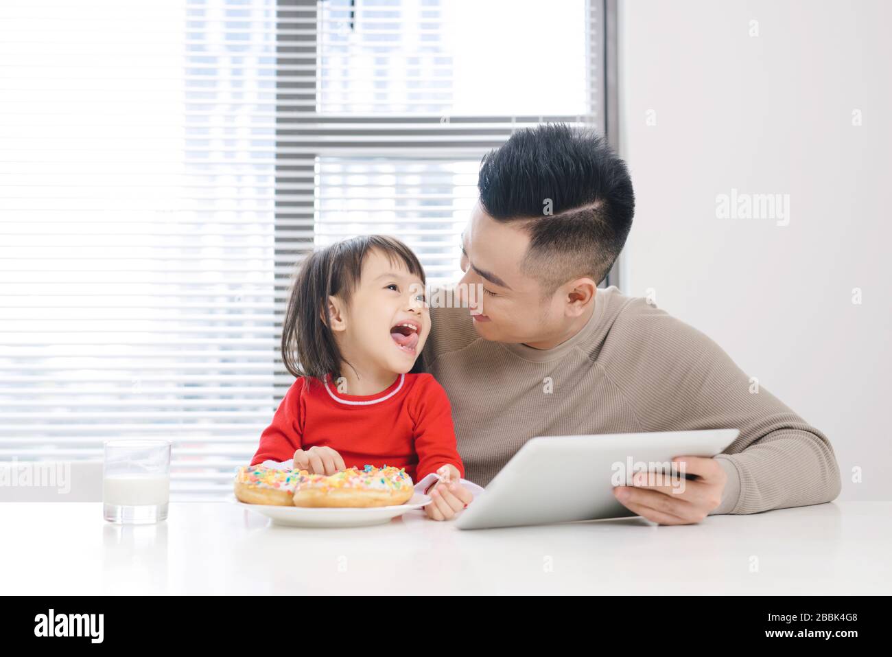 Young dad and his daughter eating pizza and using ipad Stock Photo - Alamy