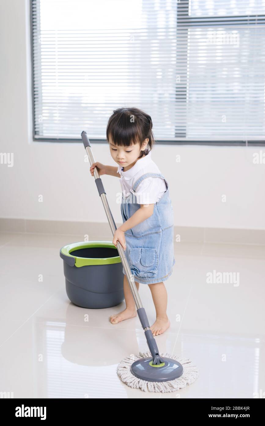 Lovely little girl doing housework in living room alone. Household ...