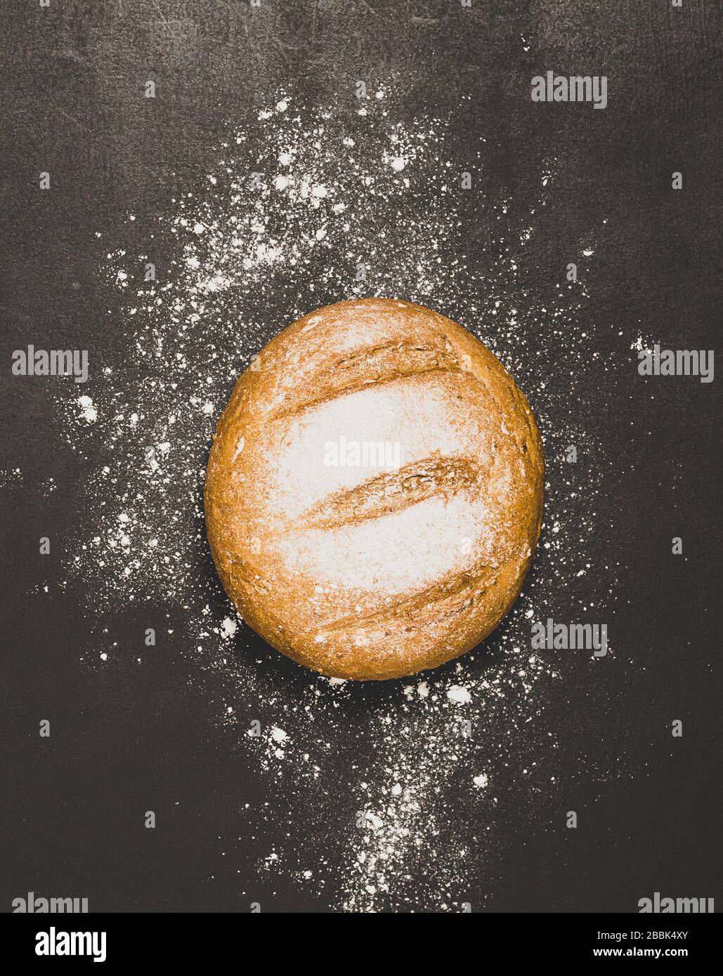 One bun of freshly baked bread on a black background. The concept of ...