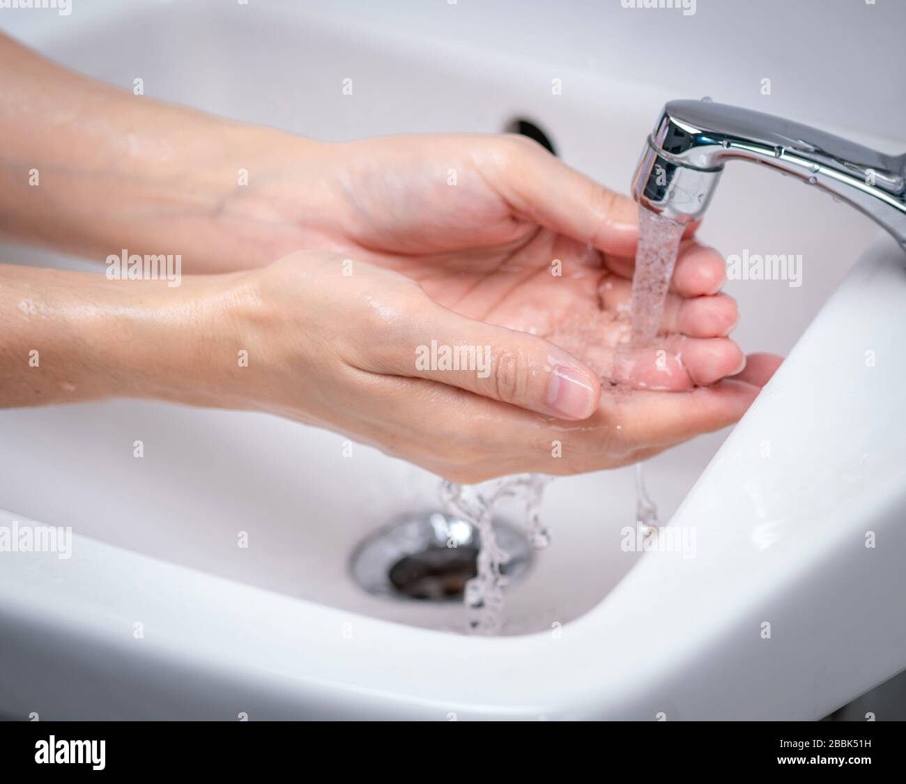 Woman washing hand with tap water in bathroom. Hand clean under faucet ...