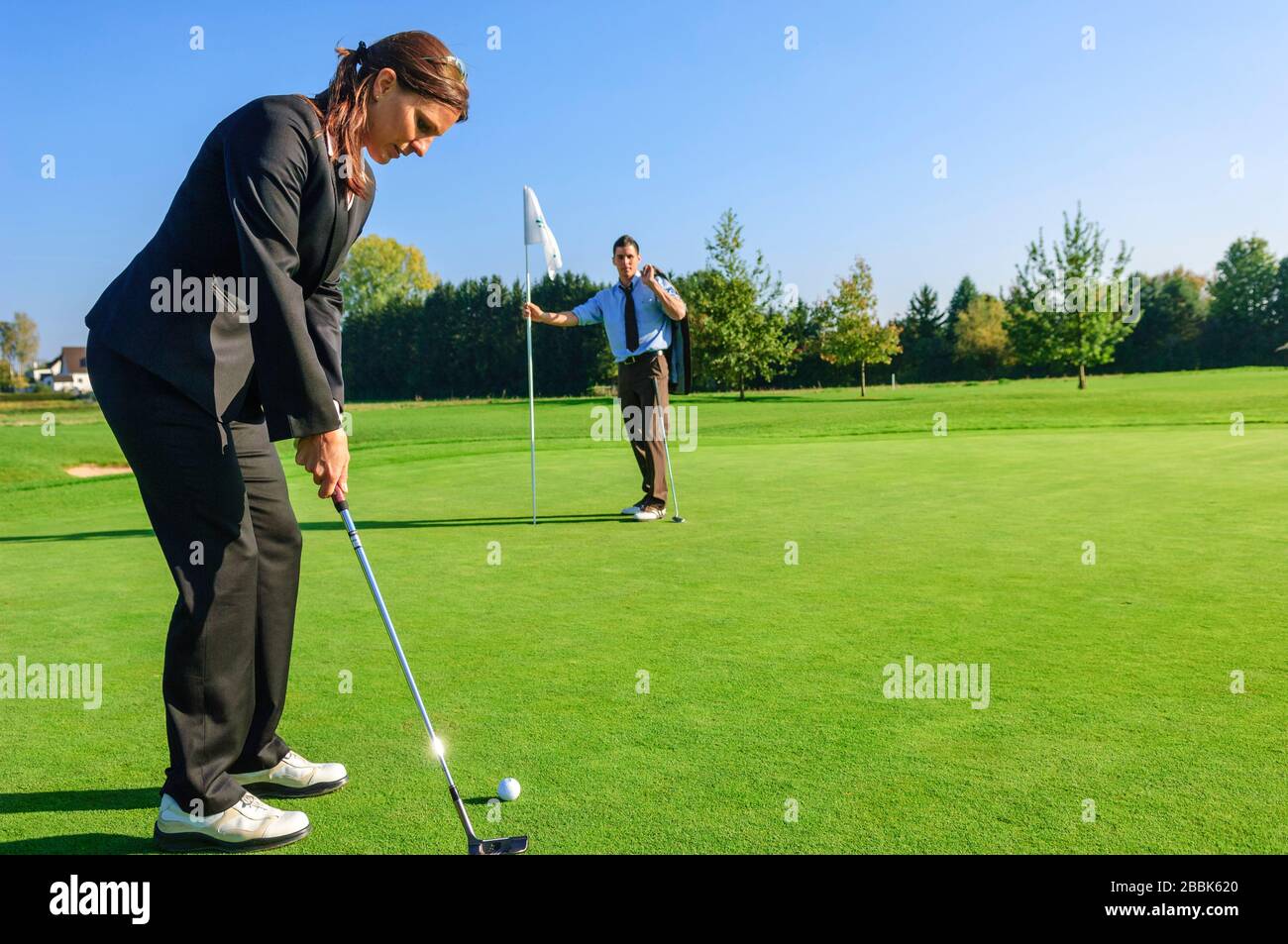 Two golfers playing after work in business outfit Stock Photo - Alamy