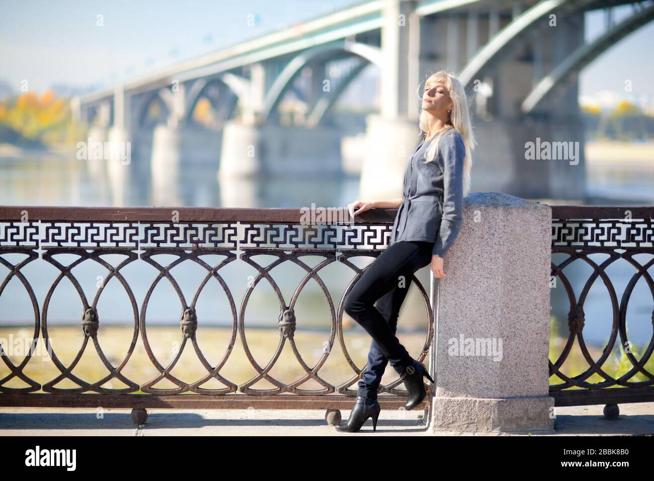 Beautiful woman leans on the railing of the bridge in the background ...