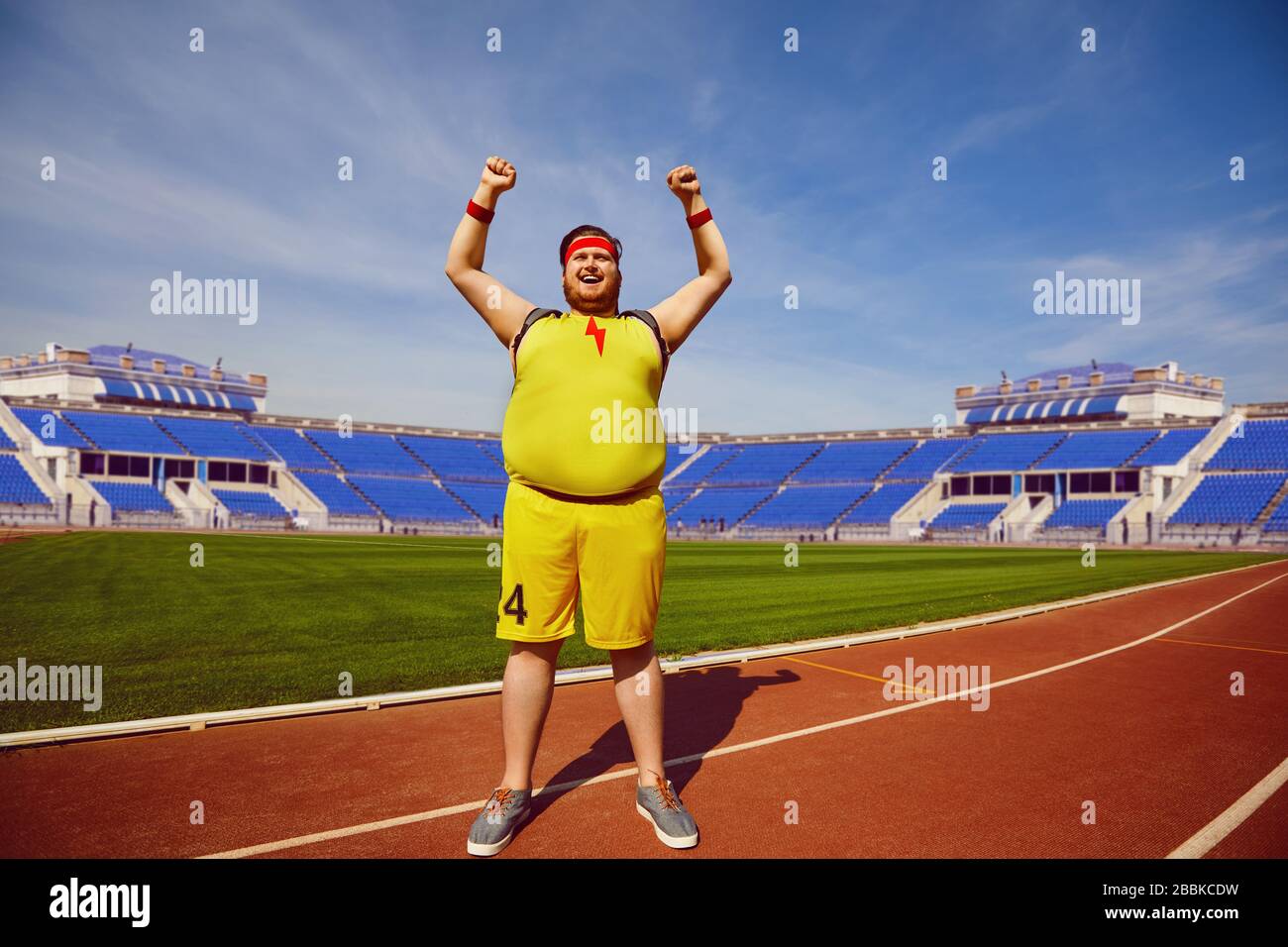 Fat man in sportswear shouts raised hands up standing in the stadium ...