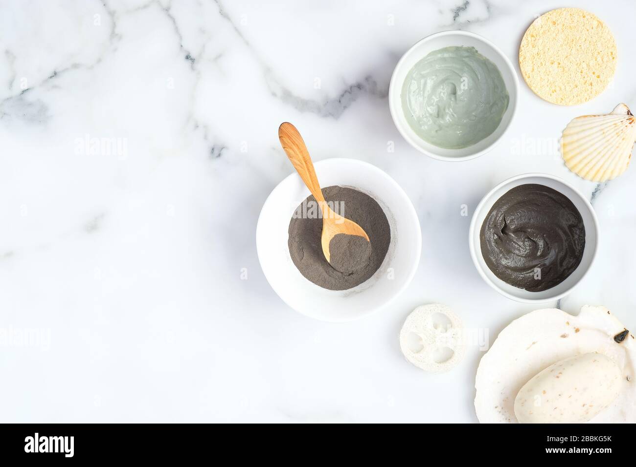 Flat lay facial clay mask, homemade soap, loofah, sponge on marble ...