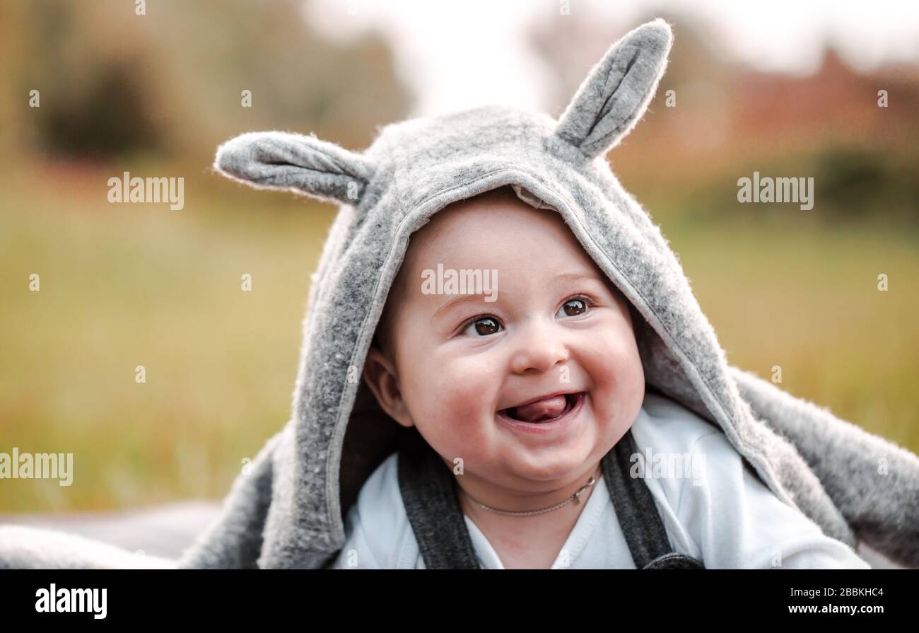 Lovely, cute adorable baby sitting on the grass outside, laughing and ...