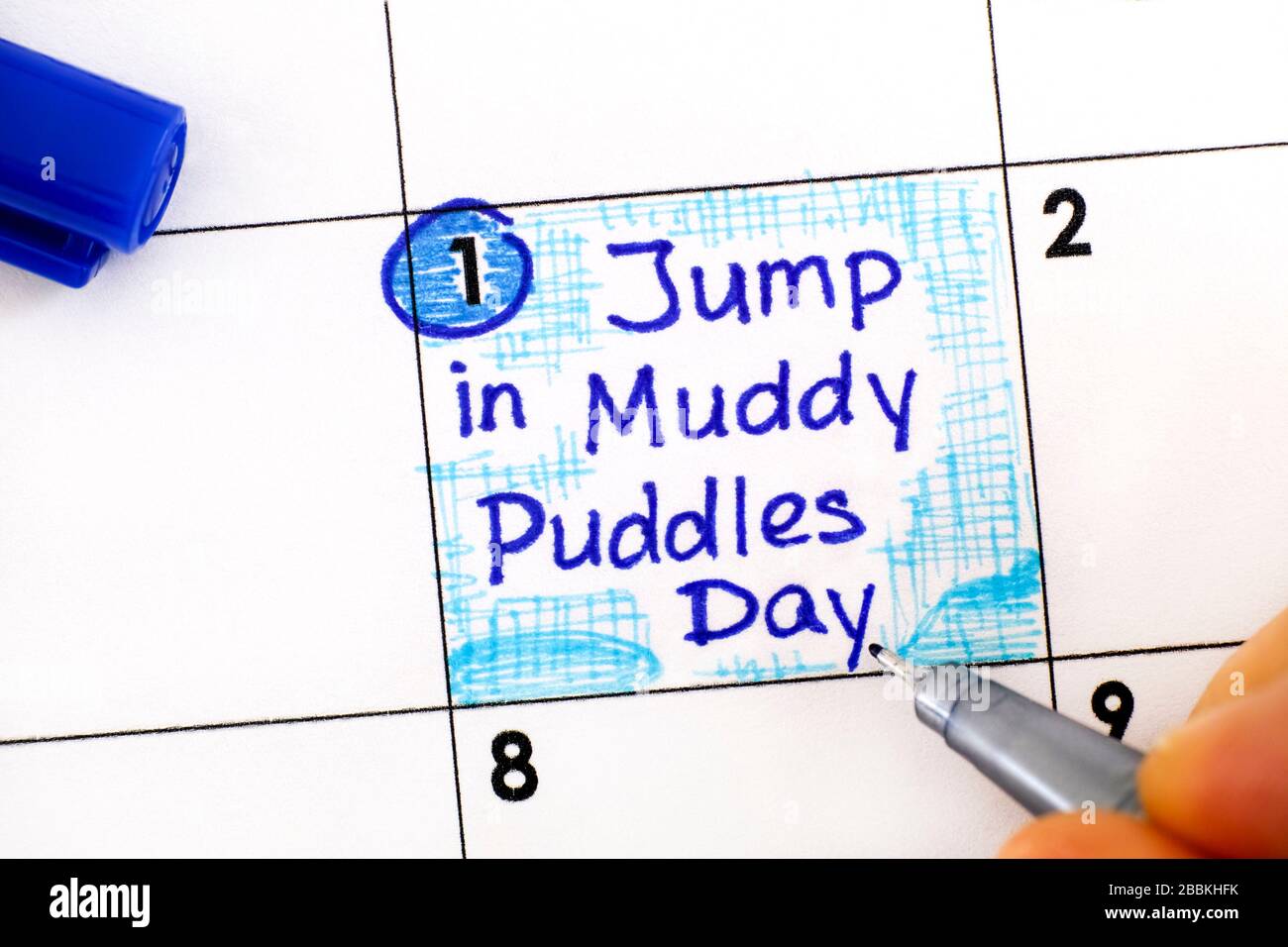 Woman fingers with pen writing reminder Jump in Muddy Puddles Day in ...