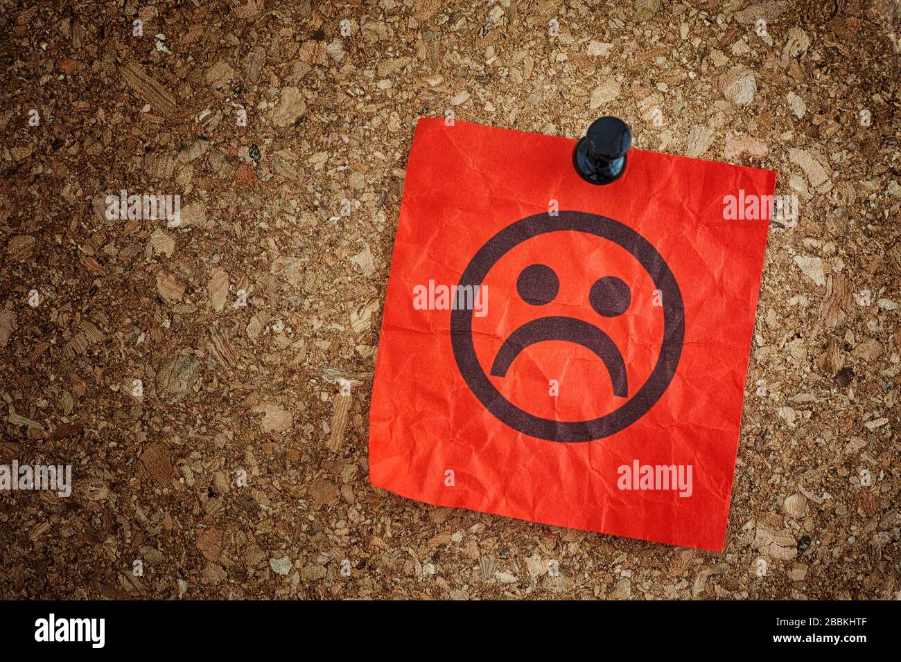 Red paper note with sad face on cork board background. Closeup Stock ...
